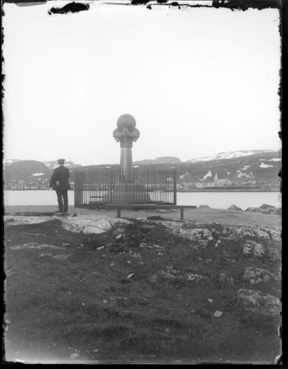 Meridianstøtten på Fuglenes i Hammerfest. En mann står med ryggen til ...