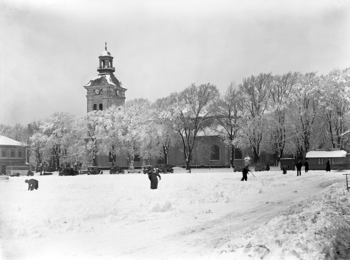 Snöröjning på Varbergs torg med kyrkan i bakgrunden. Framför den står ...