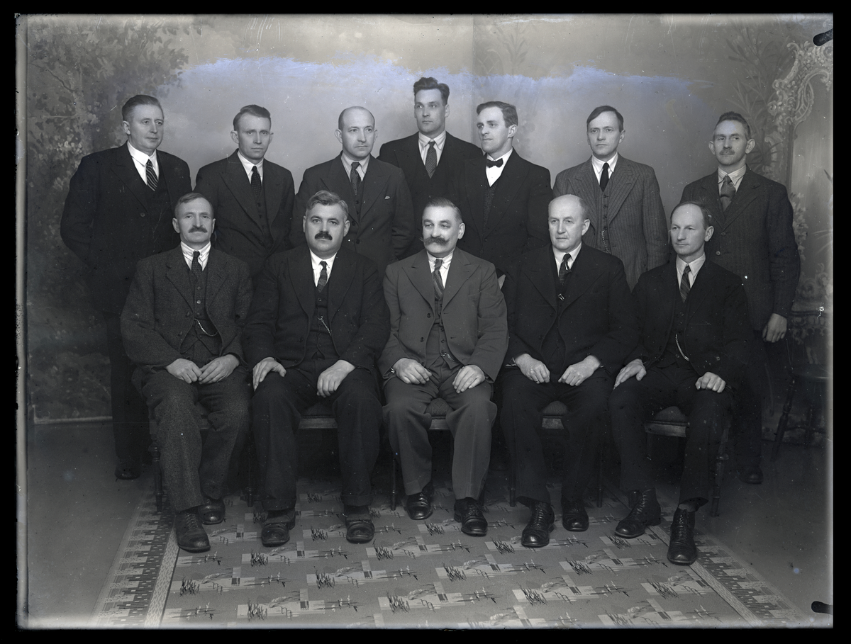 Gruppebilde. Flere menn i dress, 5 menn sitter og 7 står bak.Ordfører i ...