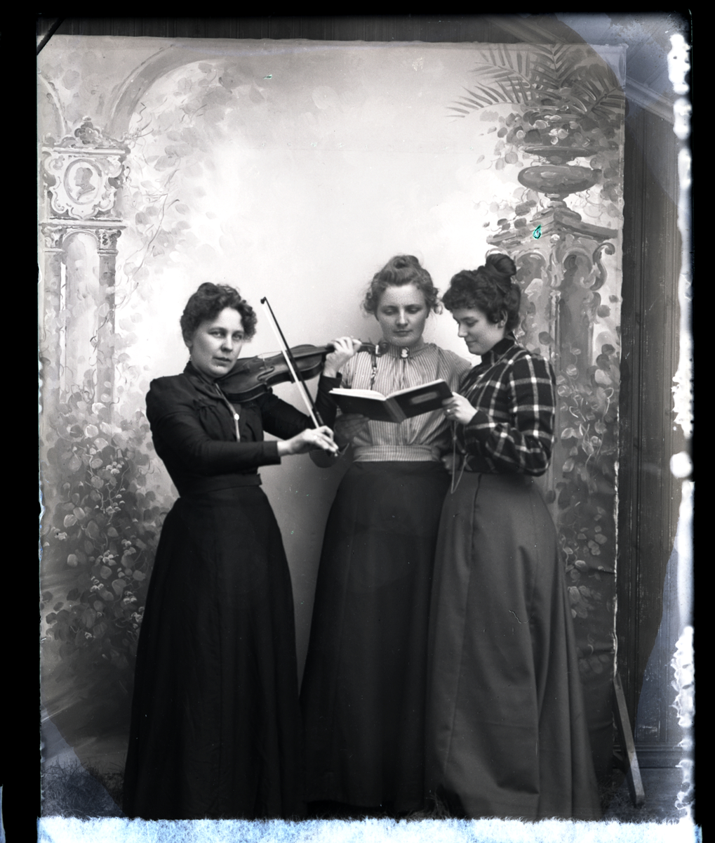 Tre kvinner, en av dem med fele/fiolin. Skrevet på papir som er festet ...