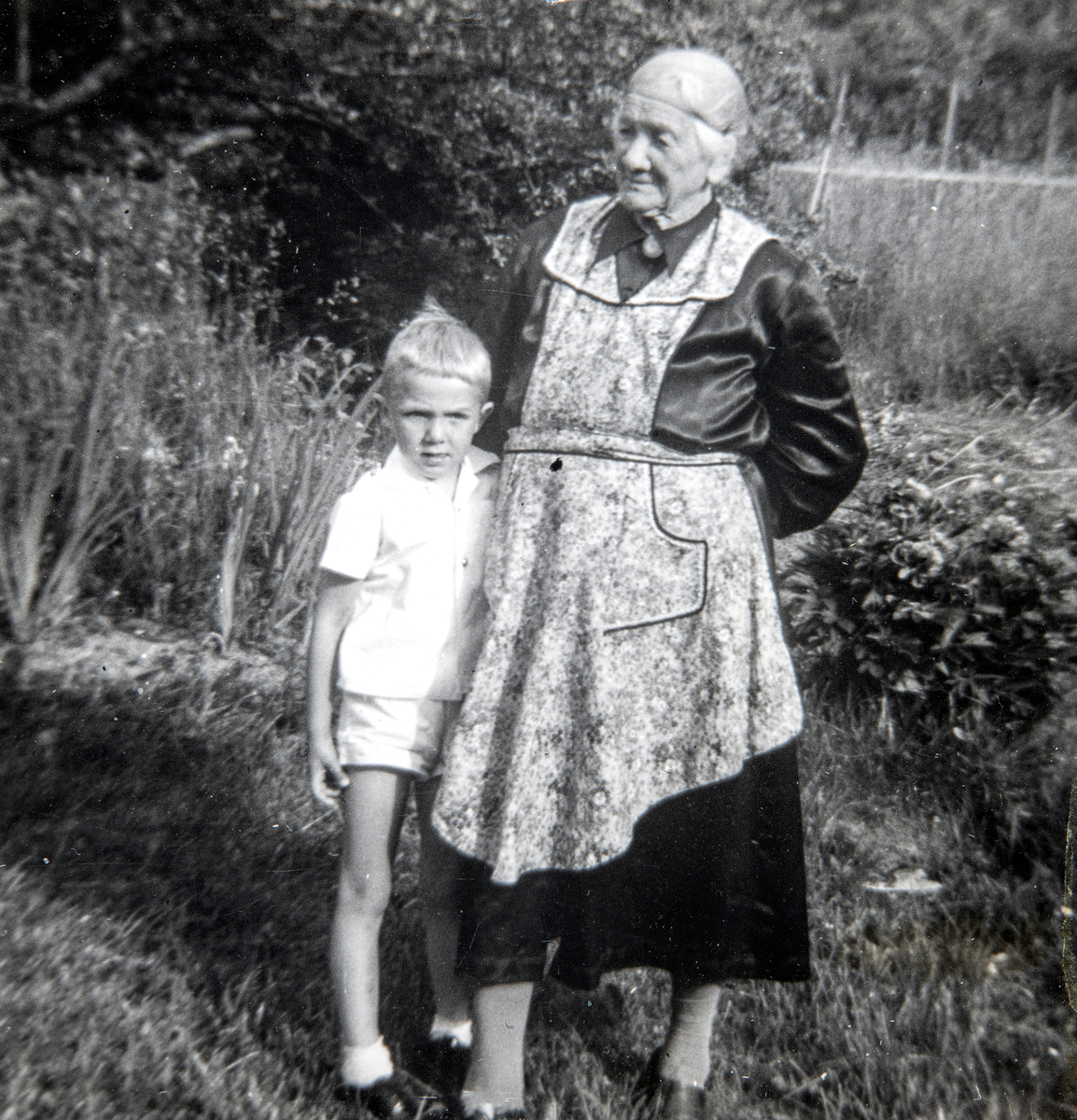 Inga Løvstad (1881-1968) og oldebarnet Stig Erik Nordnes, ute i hagen på Løvstad, Espa, 1958 ...